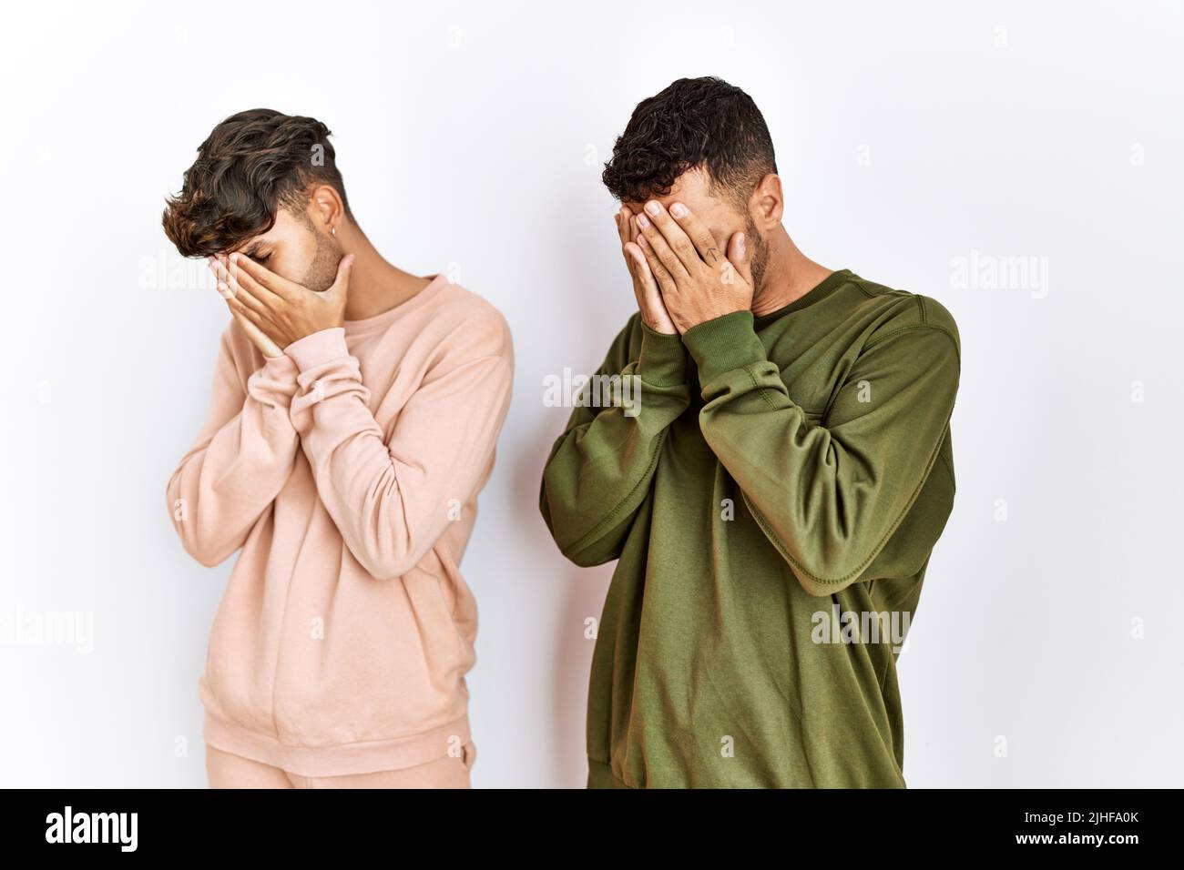 Young gay couple standing over isolated white background with sad ...