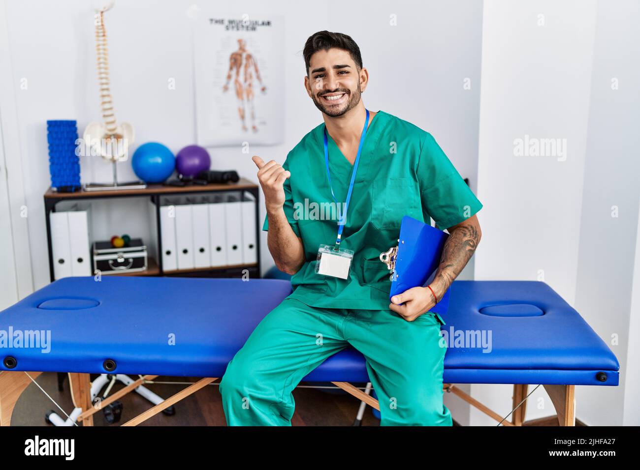 Young physiotherapist man working at pain recovery clinic pointing to ...