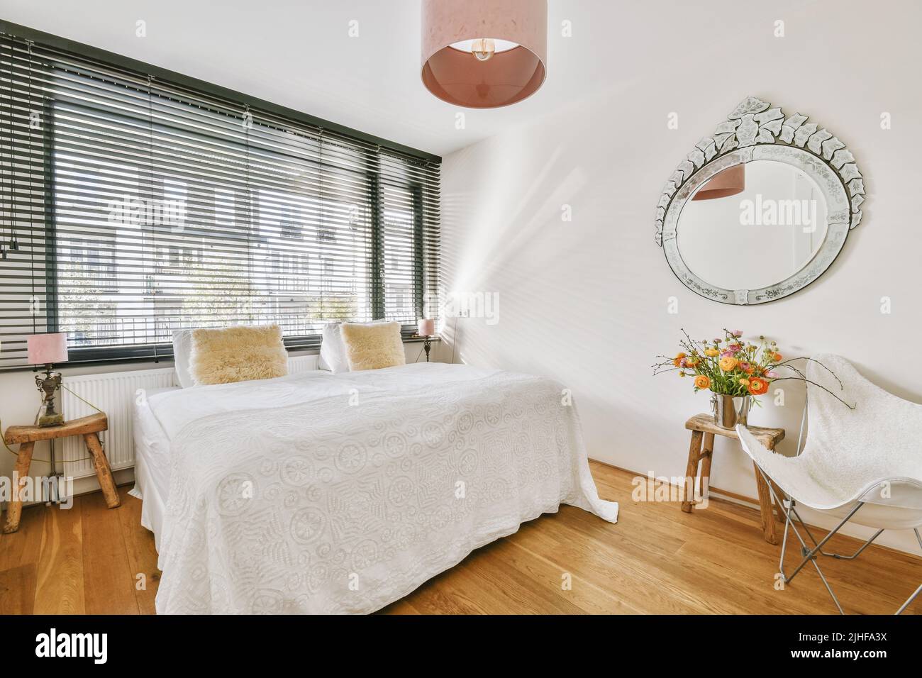 Comfortable bed located near window with curtain in light bedroom Stock ...