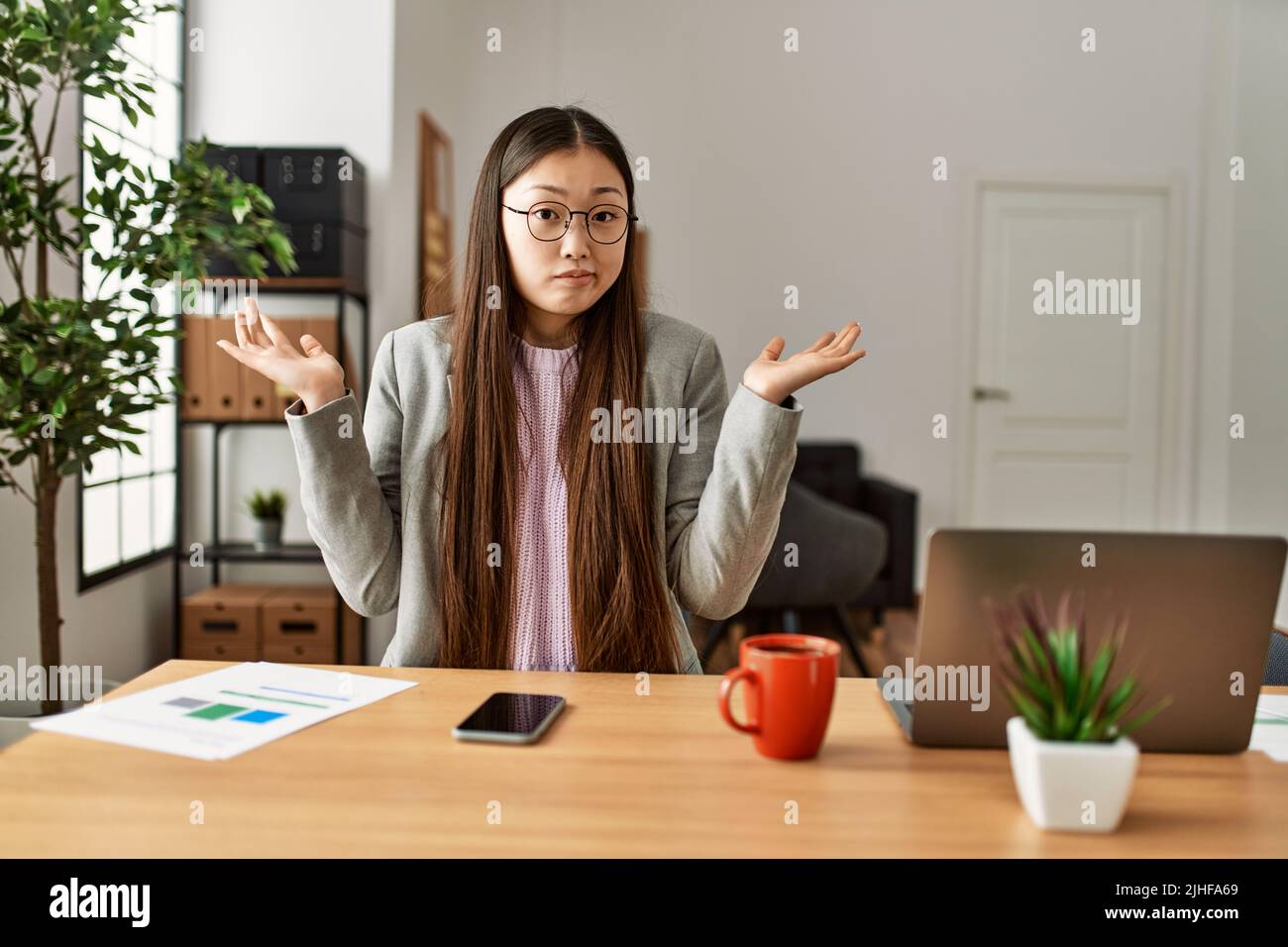 Young chinese business worker wearing business style sitting on desk at ...