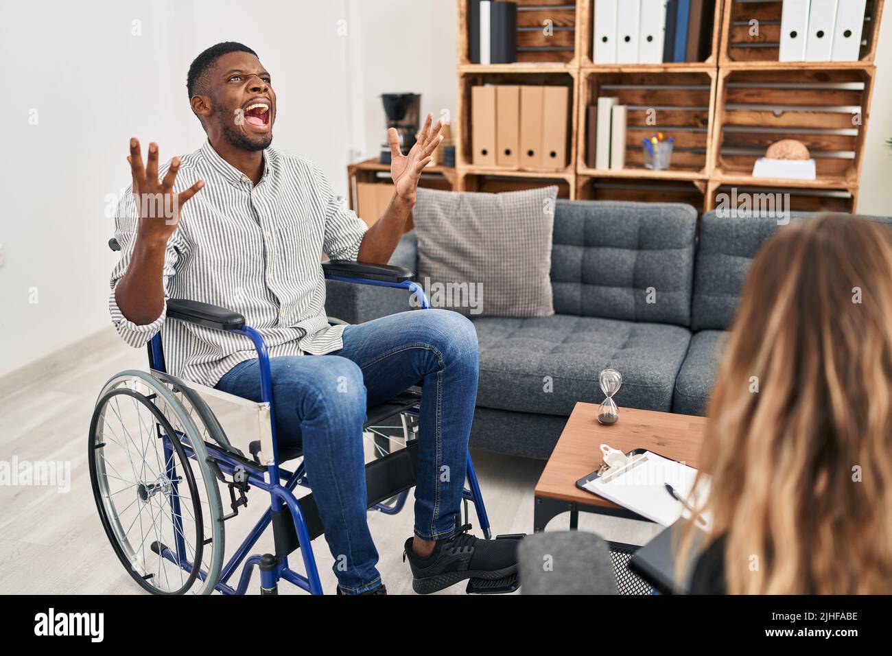 African american man doing therapy sitting on wheelchair crazy and mad ...