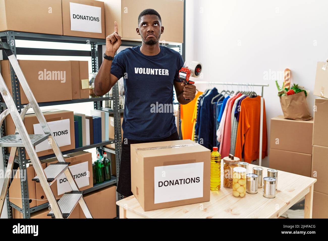 Young african american volunteer man packing donations box for charity ...