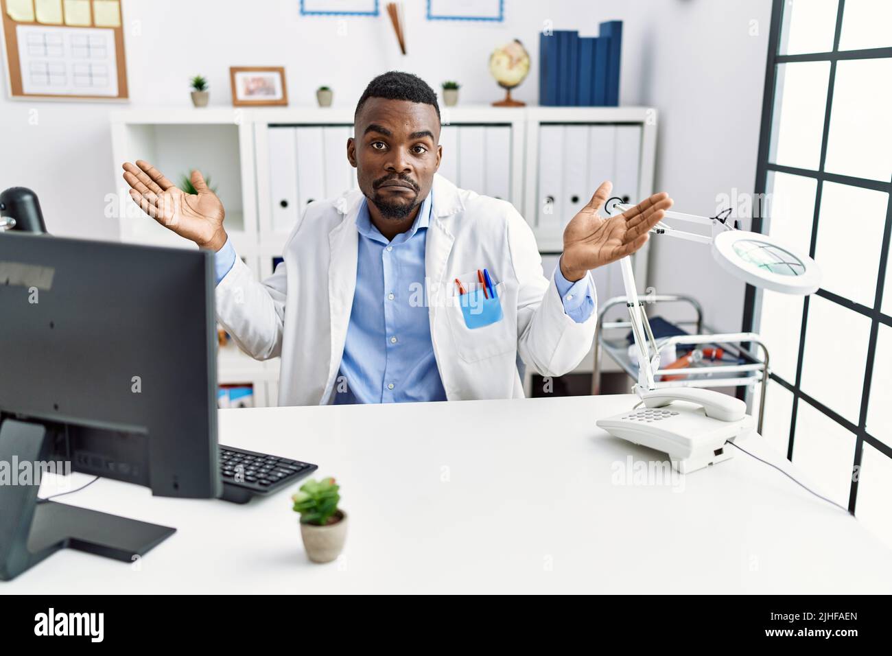 Young african doctor man wearing stethoscope at the clinic clueless and ...