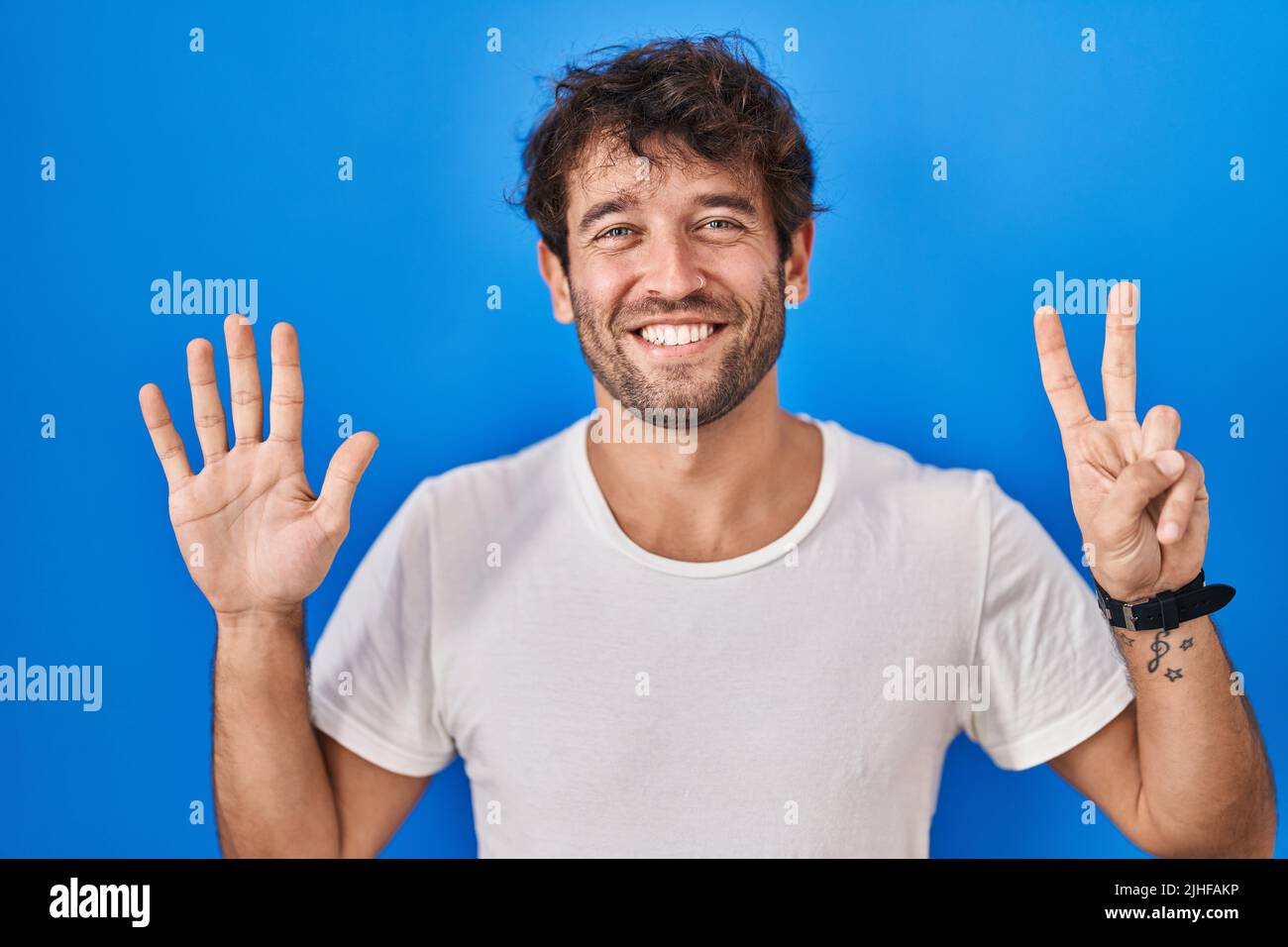 Hispanic young man standing over blue background showing and pointing ...
