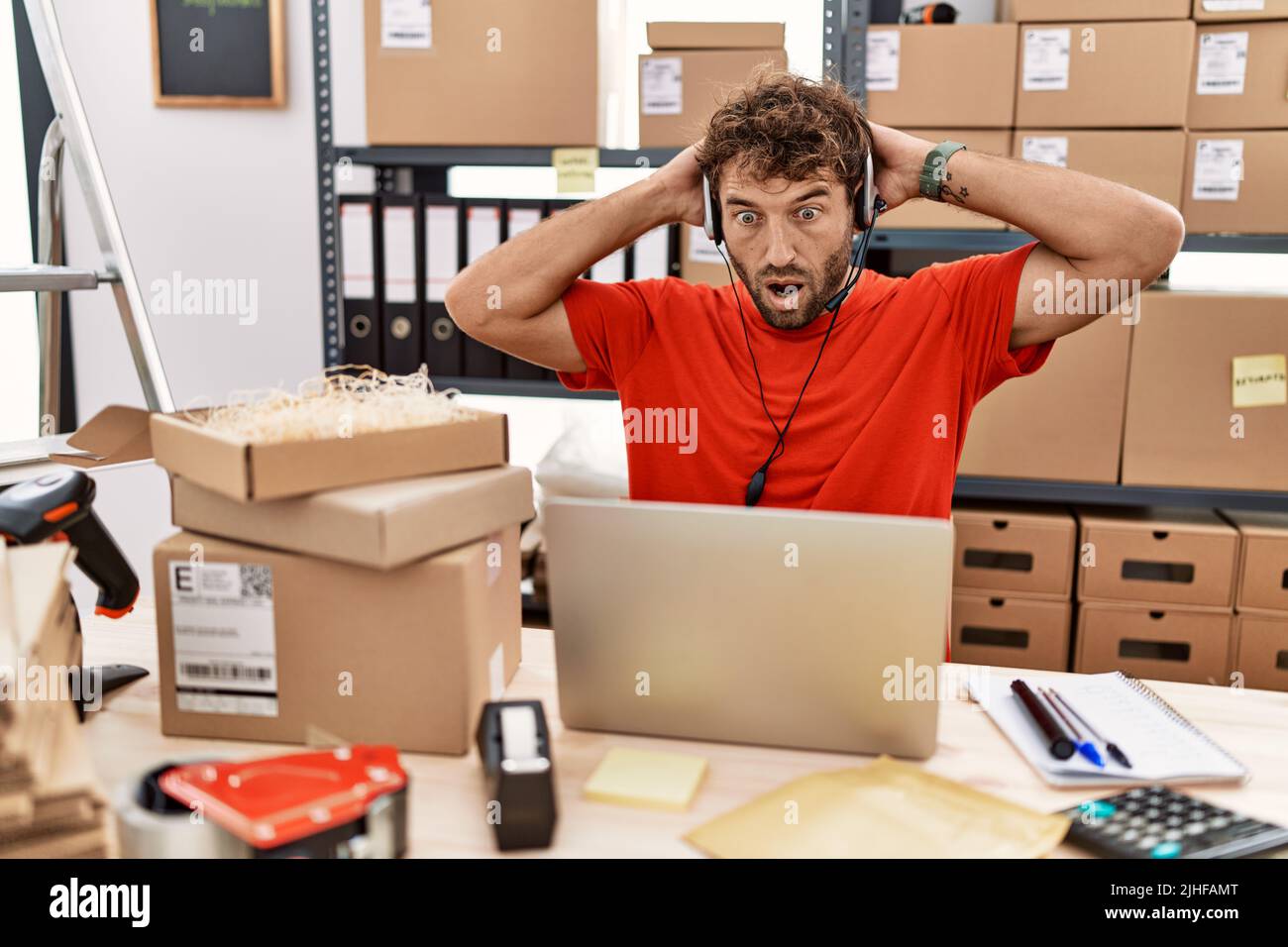 Young hispanic call center agent man working at warehouse crazy and ...