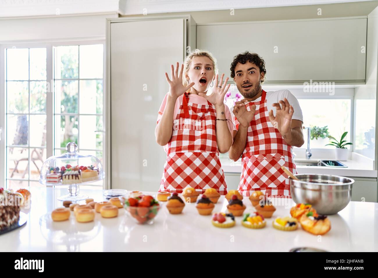 Couple of wife and husband cooking pastries at the kitchen afraid and ...