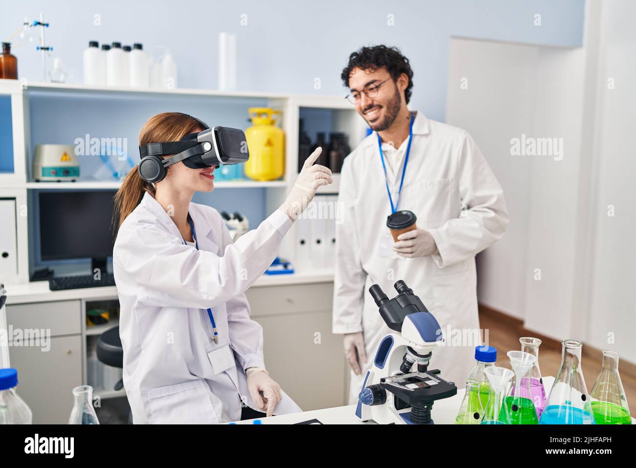 Man and woman scientist partners using vr goggles and drinking coffee ...