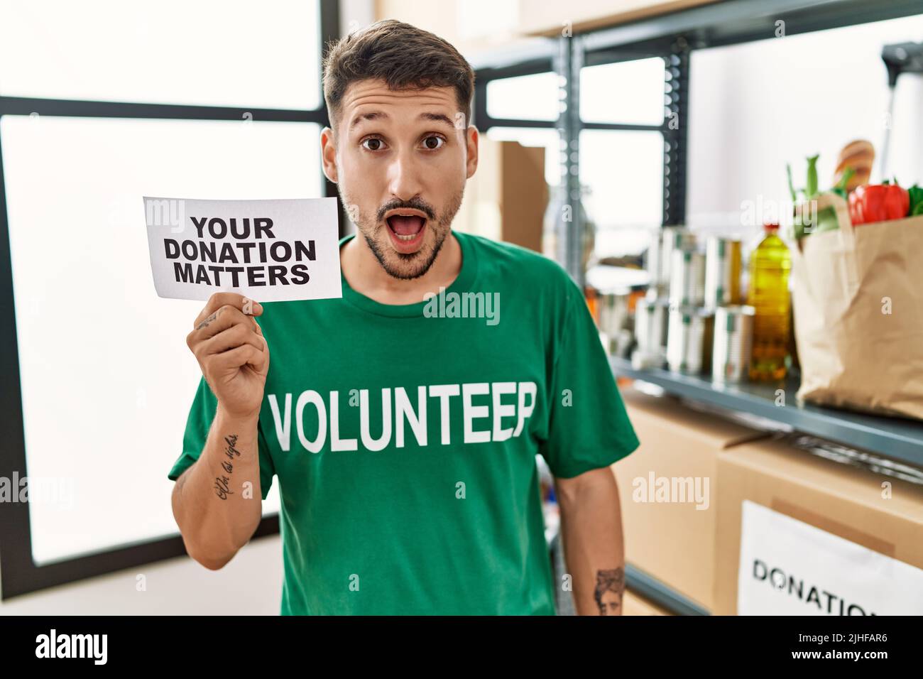 Young volunteer man holding your donation matters banner scared and ...
