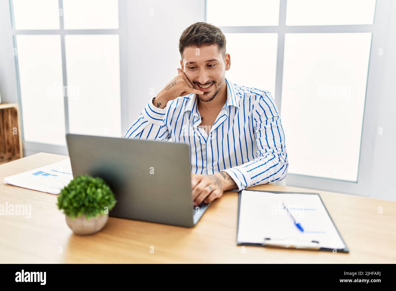 Young handsome man with beard working at the office using computer ...