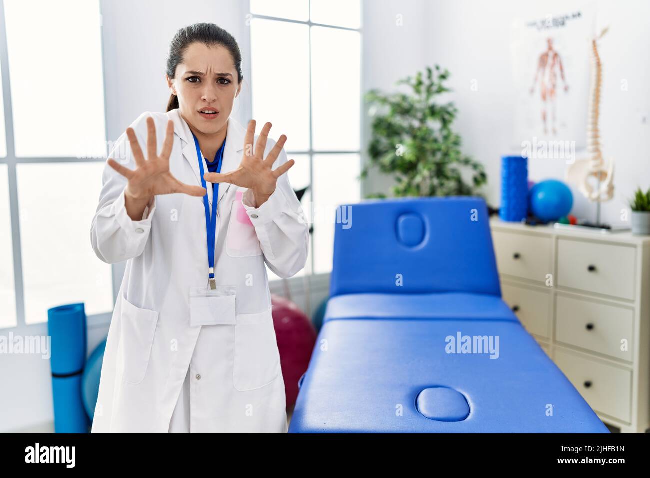 Young doctor woman working at pain recovery clinic afraid and terrified ...