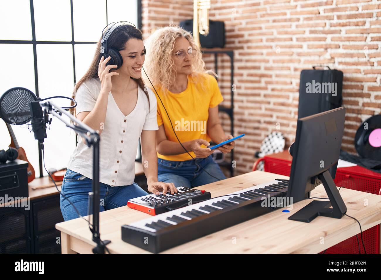 Two women musicians composing song using keyboard and touchpad at music ...