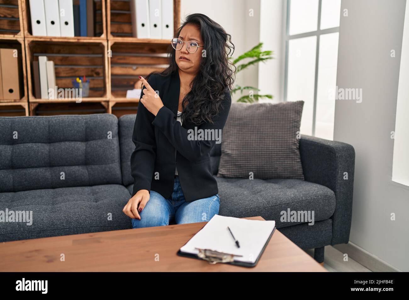 Young asian woman at consultation office pointing aside worried and ...