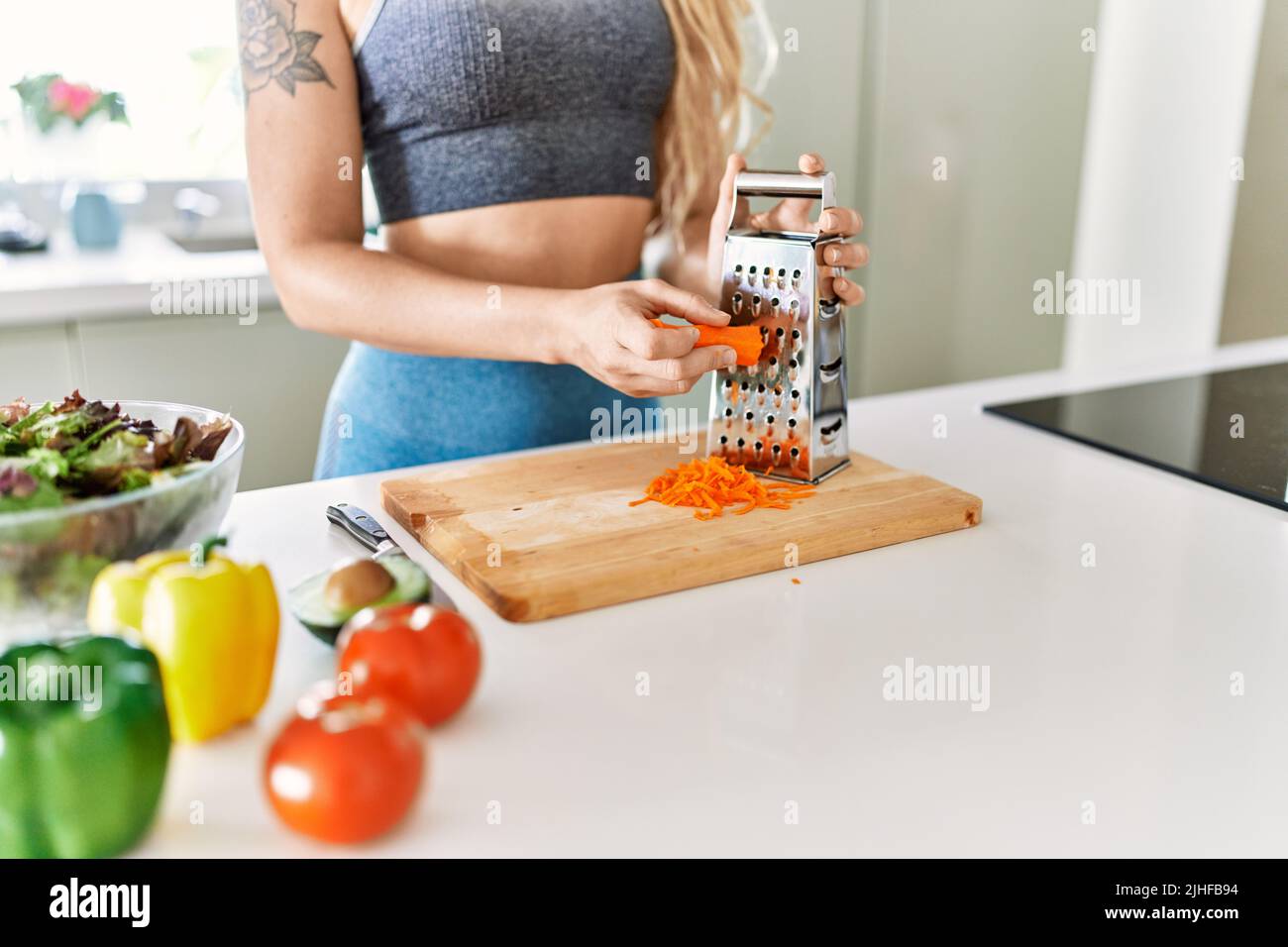Young woman scratching carrot for salad at kitchen Stock Photo - Alamy