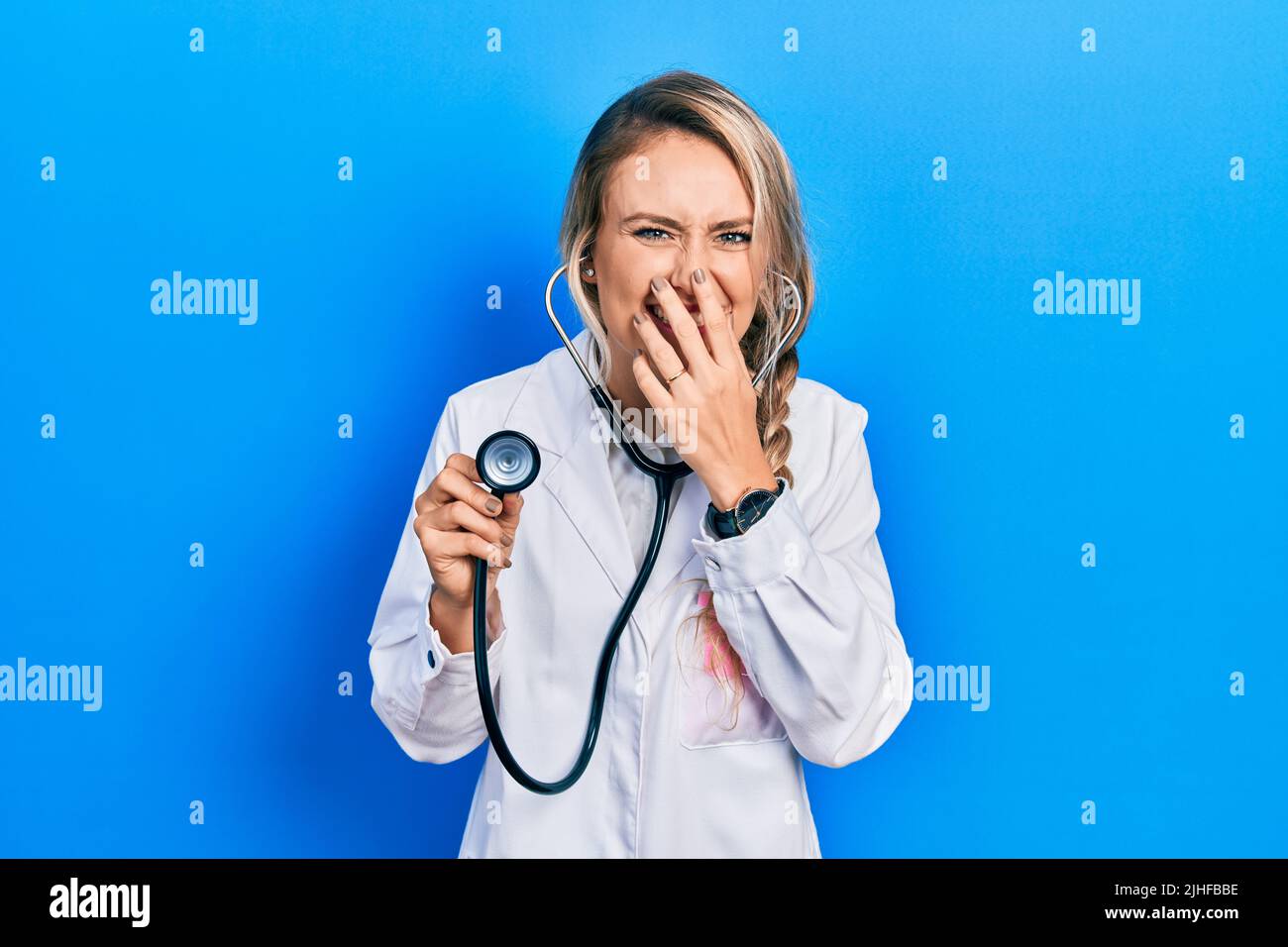 Beautiful young blonde doctor woman holding stethoscope laughing and ...