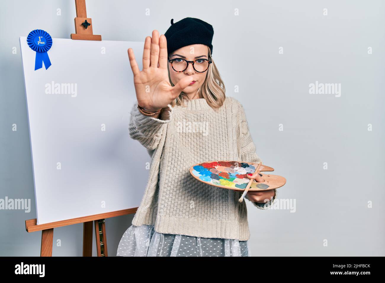 Beautiful caucasian woman drawing with palette on easel stand winner ...