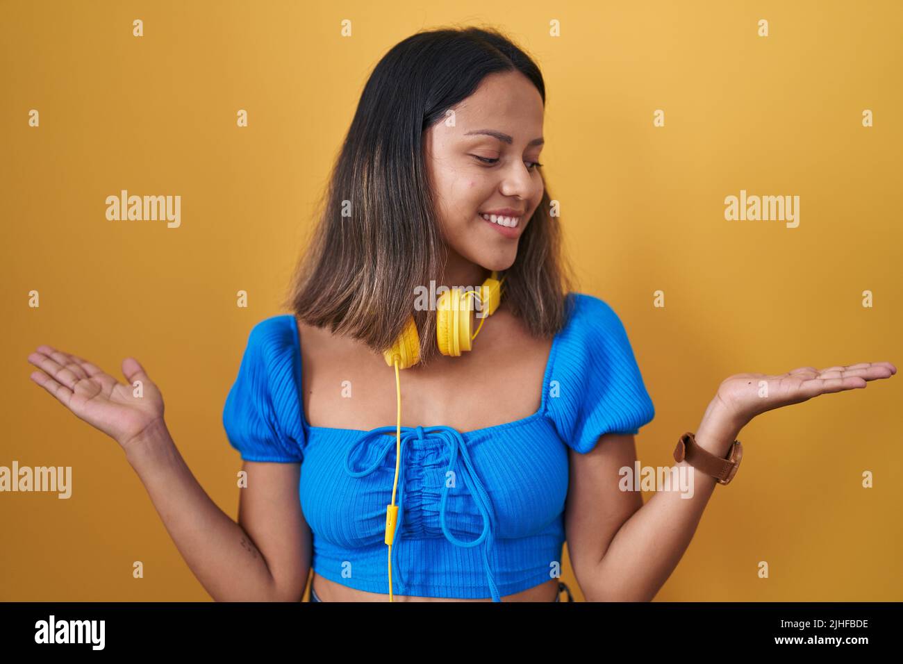 Hispanic young woman standing over yellow background smiling showing ... Hispanic young woman standing over yellow background smiling showing ...