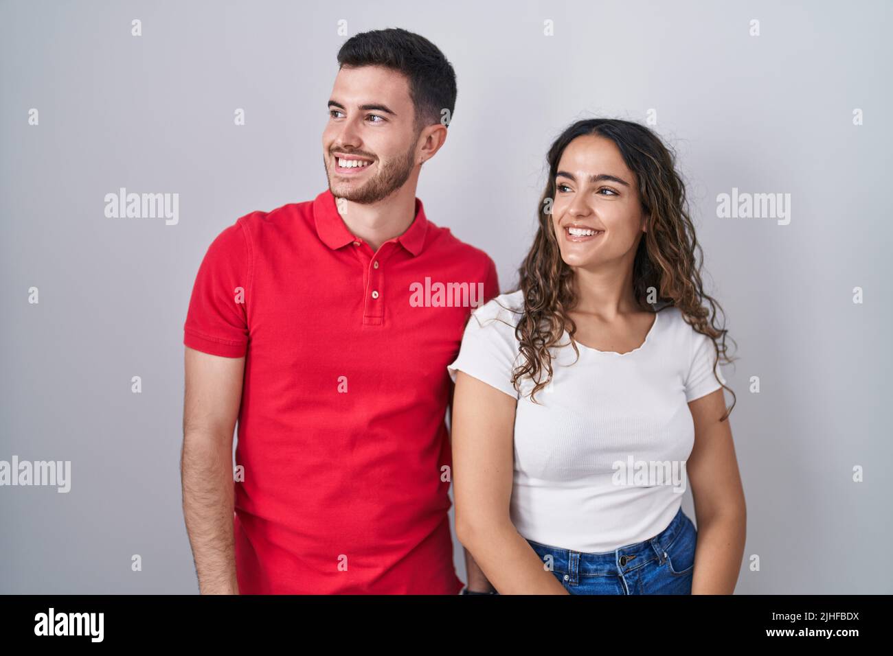 Young hispanic couple standing over isolated background looking away to ...