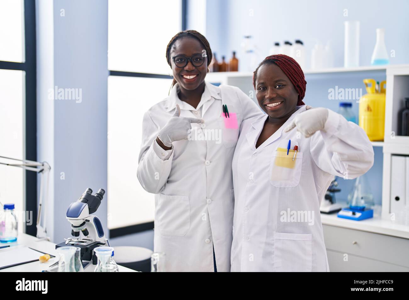 Two african women working at scientist laboratory pointing finger to ...