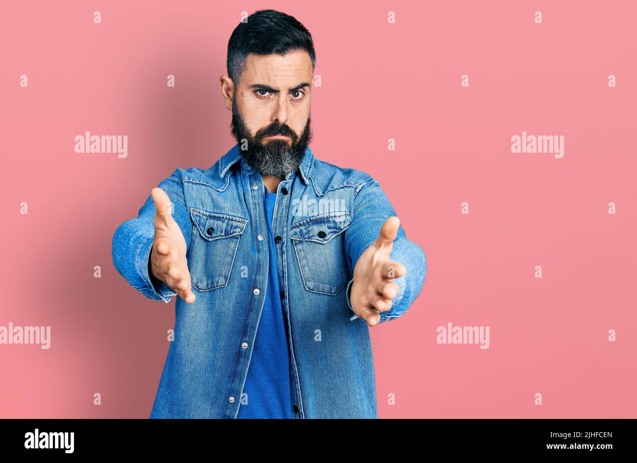 Hispanic man with beard with open arms doing hug gesture depressed and ...