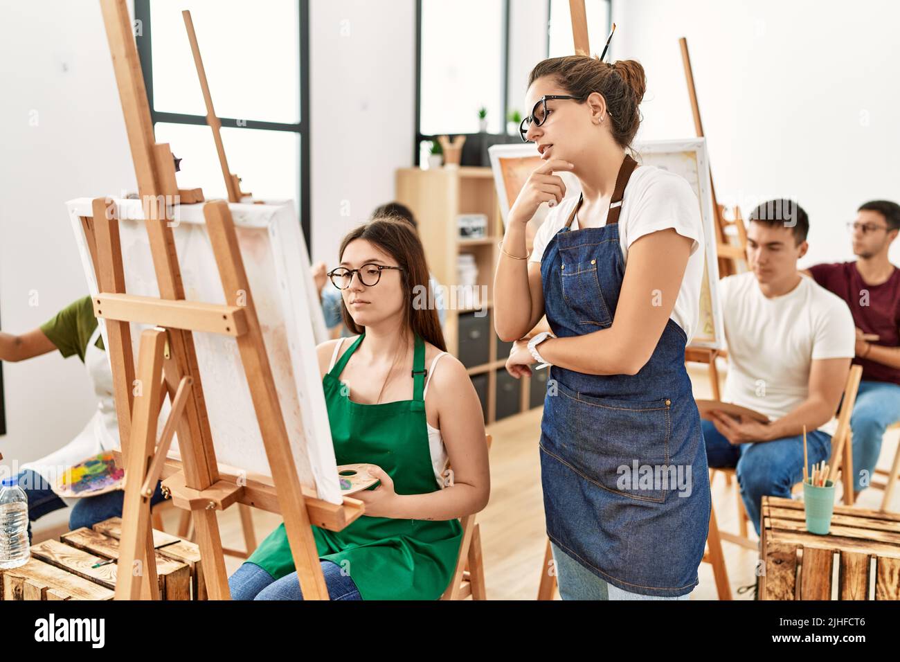 Paint teacher looking draw of student at art studio Stock Photo - Alamy