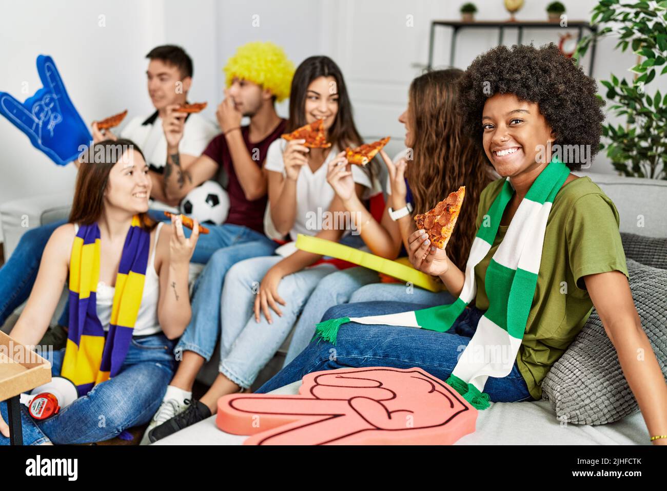 Group of young friends watching and supporting soccer match eating ...