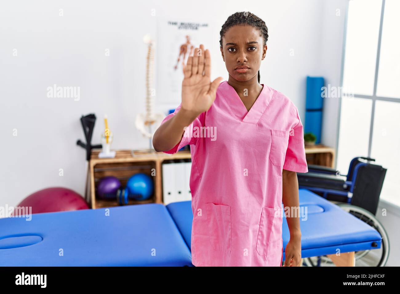 Young african american woman working at pain recovery clinic doing stop ...