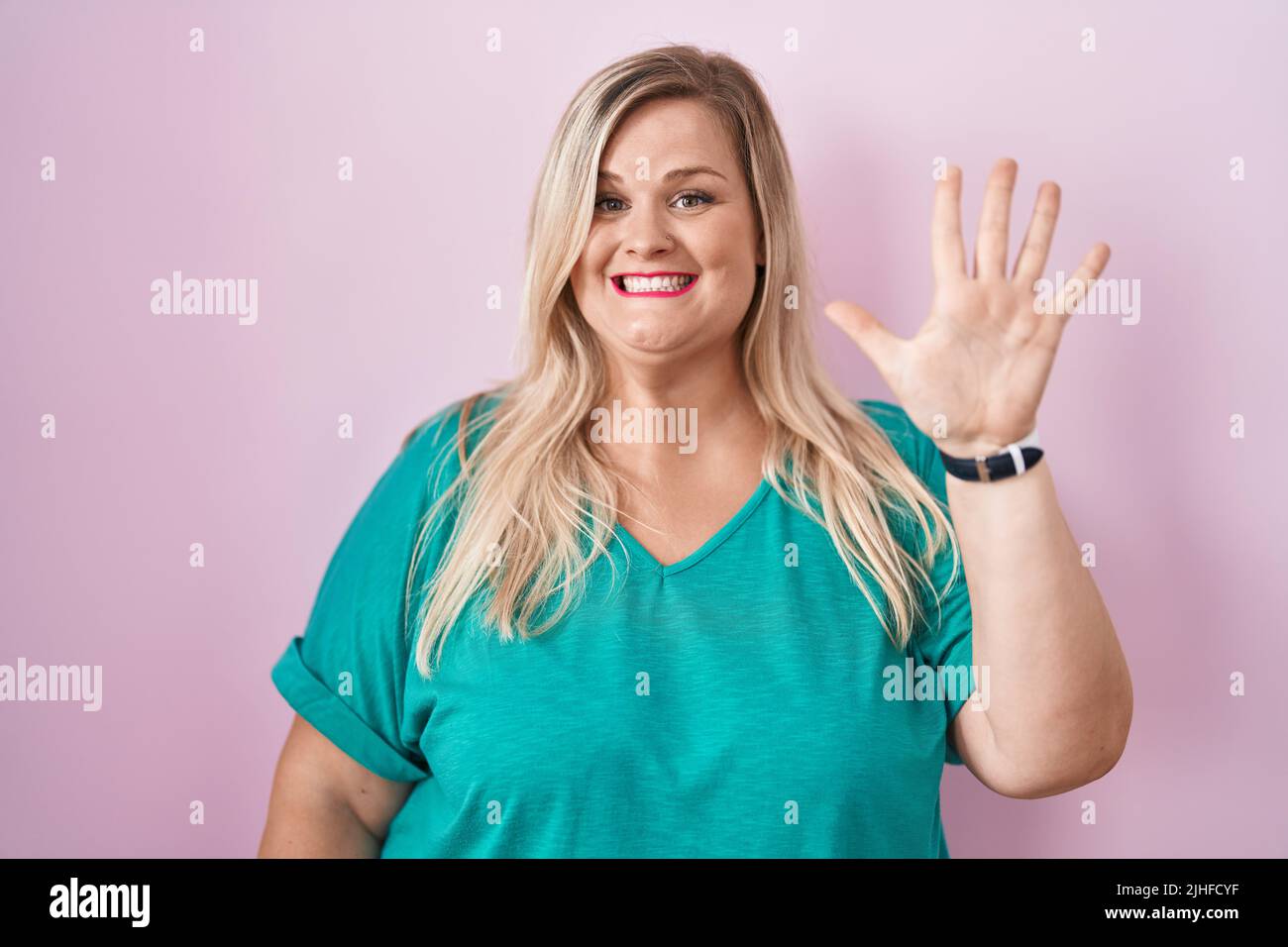 Caucasian plus size woman standing over pink background showing and ...