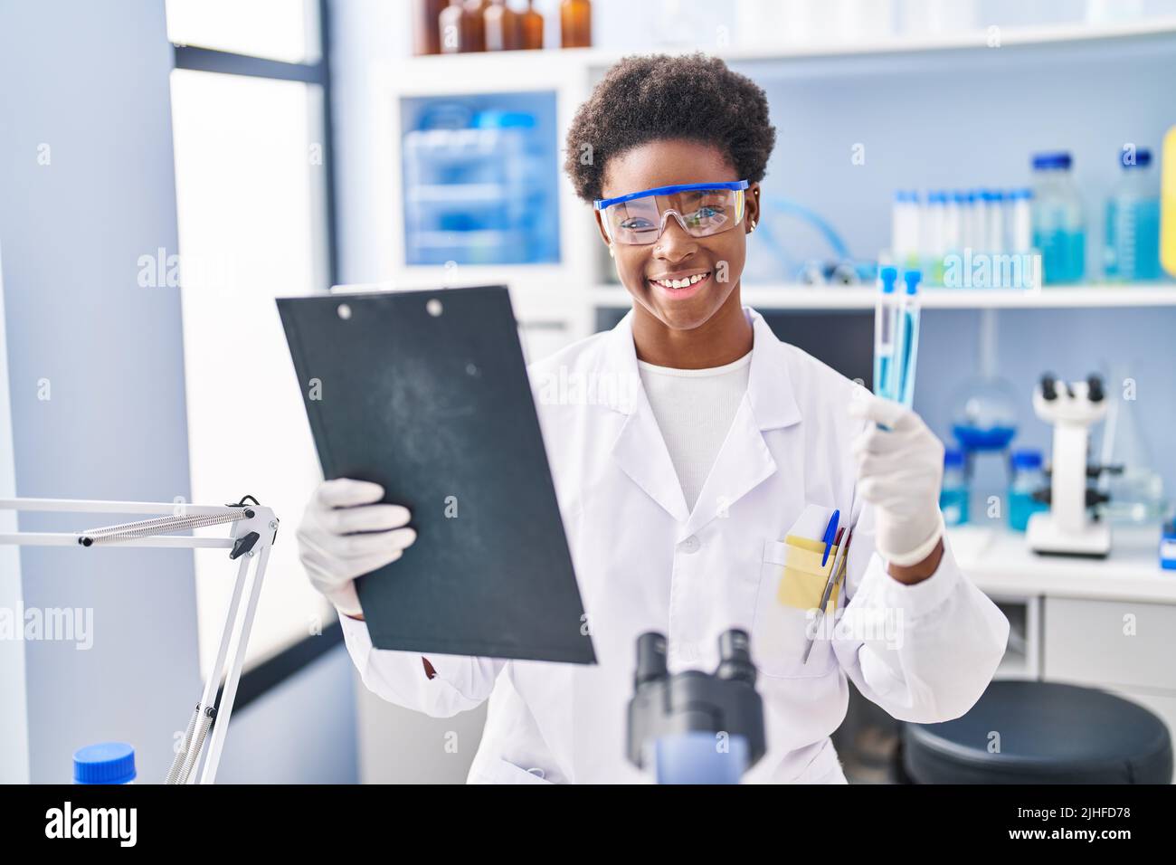 African american woman wearing scientist uniform reading document ...