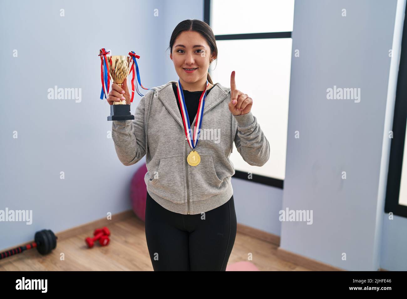 Young latin woman holding winner trophy smiling with an idea or ...