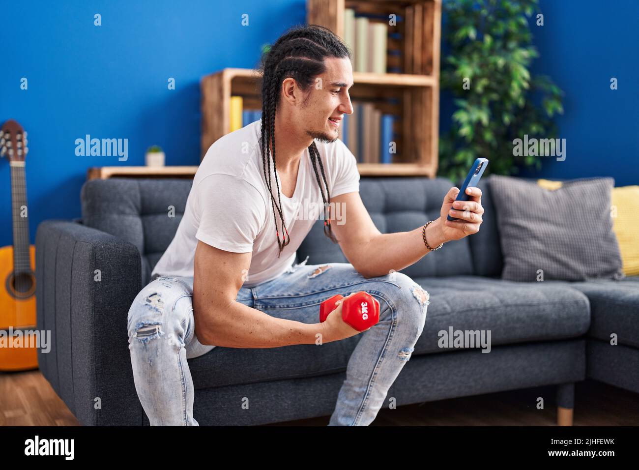 Young man training with dumbbell make selfie by smartphone at home ...