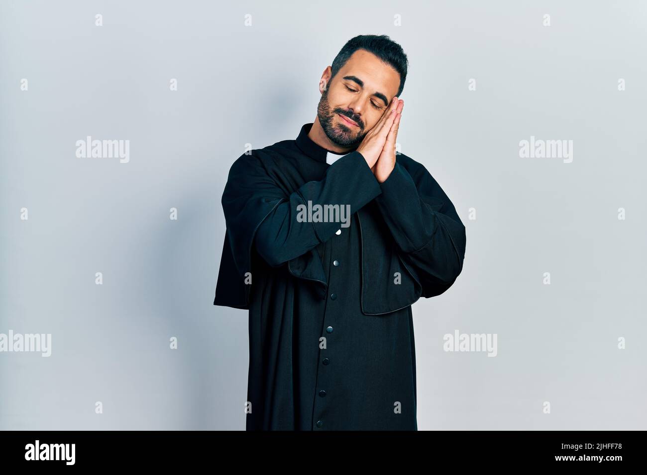 Handsome hispanic man with beard wearing catholic priest robe sleeping ...