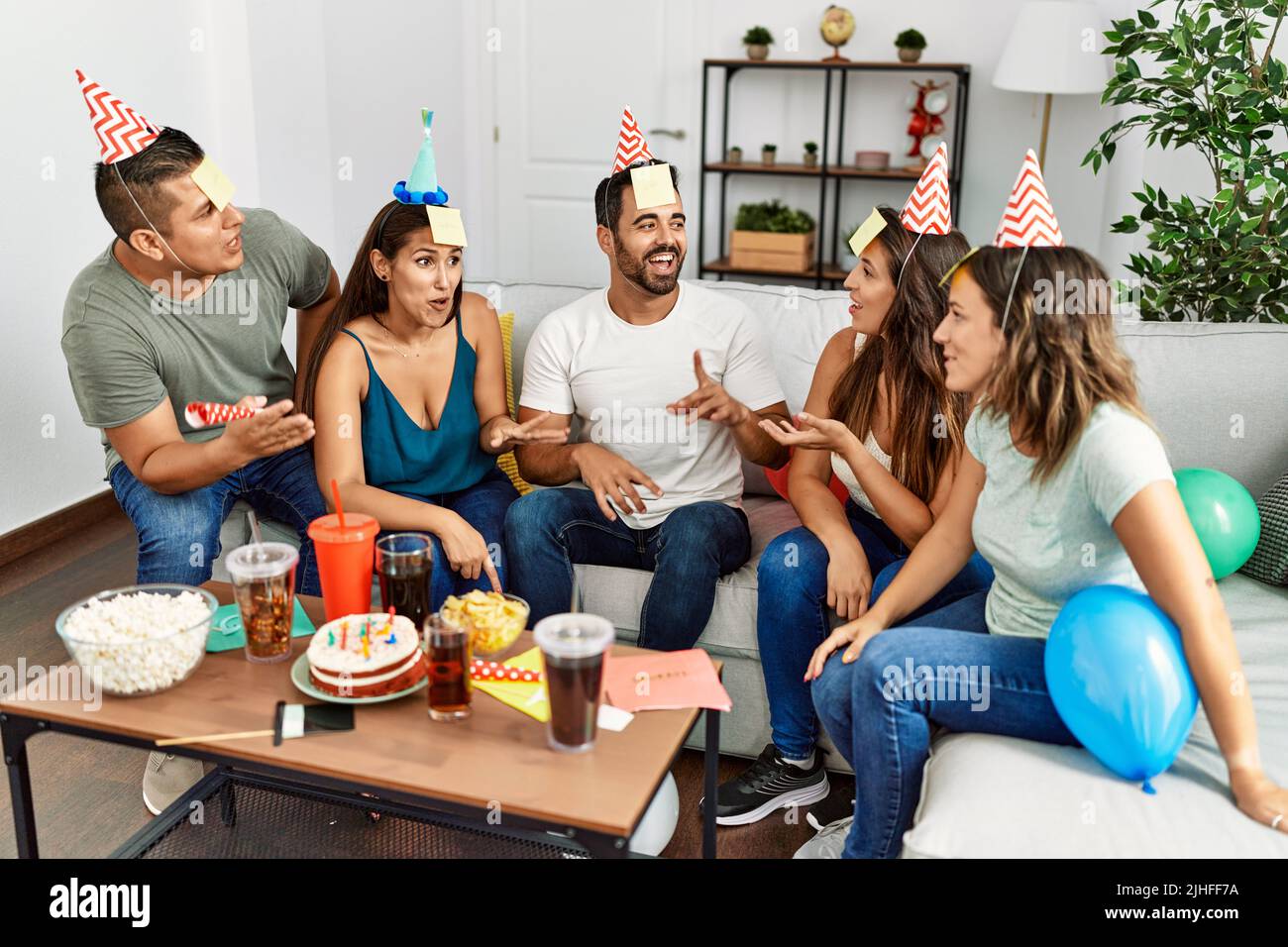 Group of young hispanic friends having birthday party playing funny ...