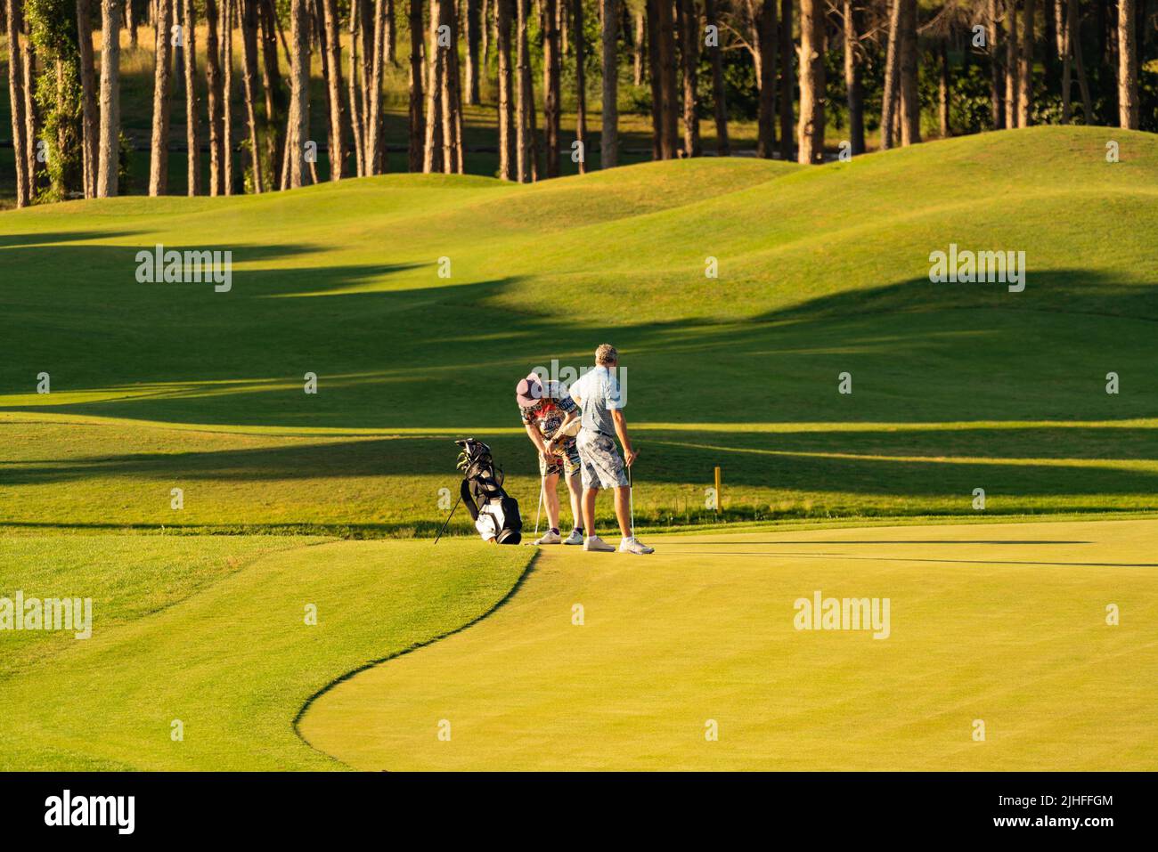 Finishing shot on the green of a golf course two men Stock Photo - Alamy