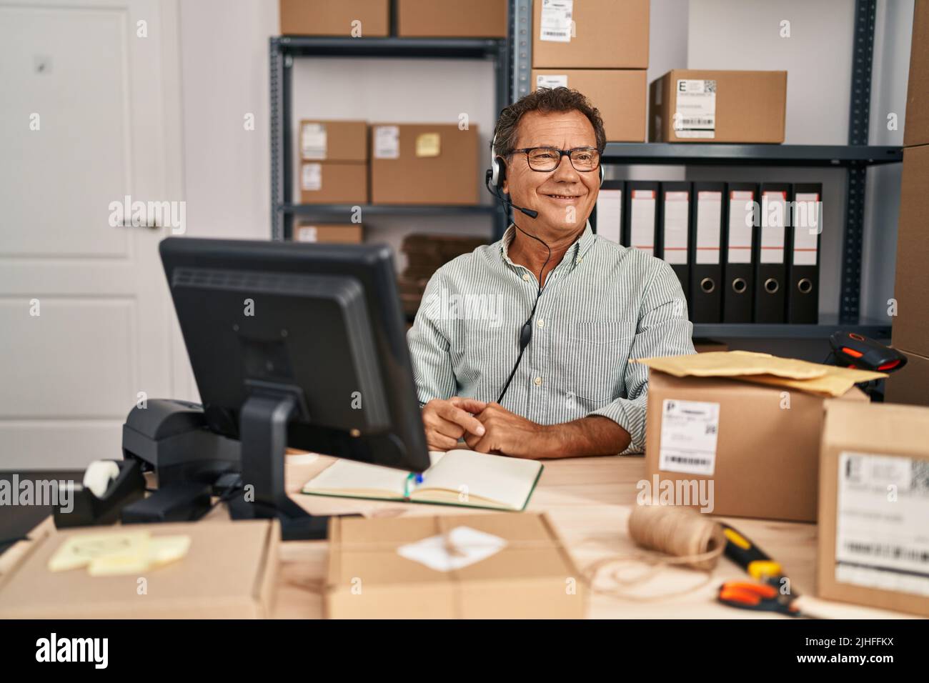 Senior man working at small business ecommerce wearing headset looking ...