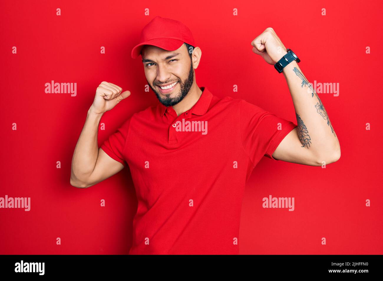 Hispanic Man With Beard Wearing Delivery Uniform And Cap Showing Arms