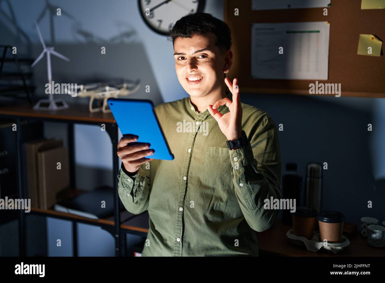 Non binary person using touchpad device at night smiling positive doing ...