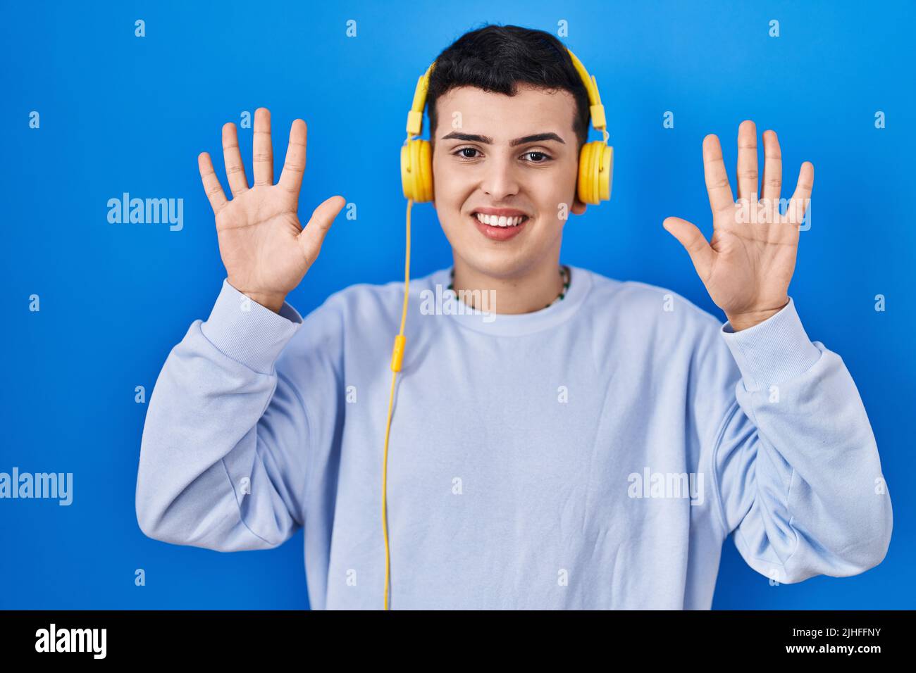 Non binary person listening to music using headphones showing and ...