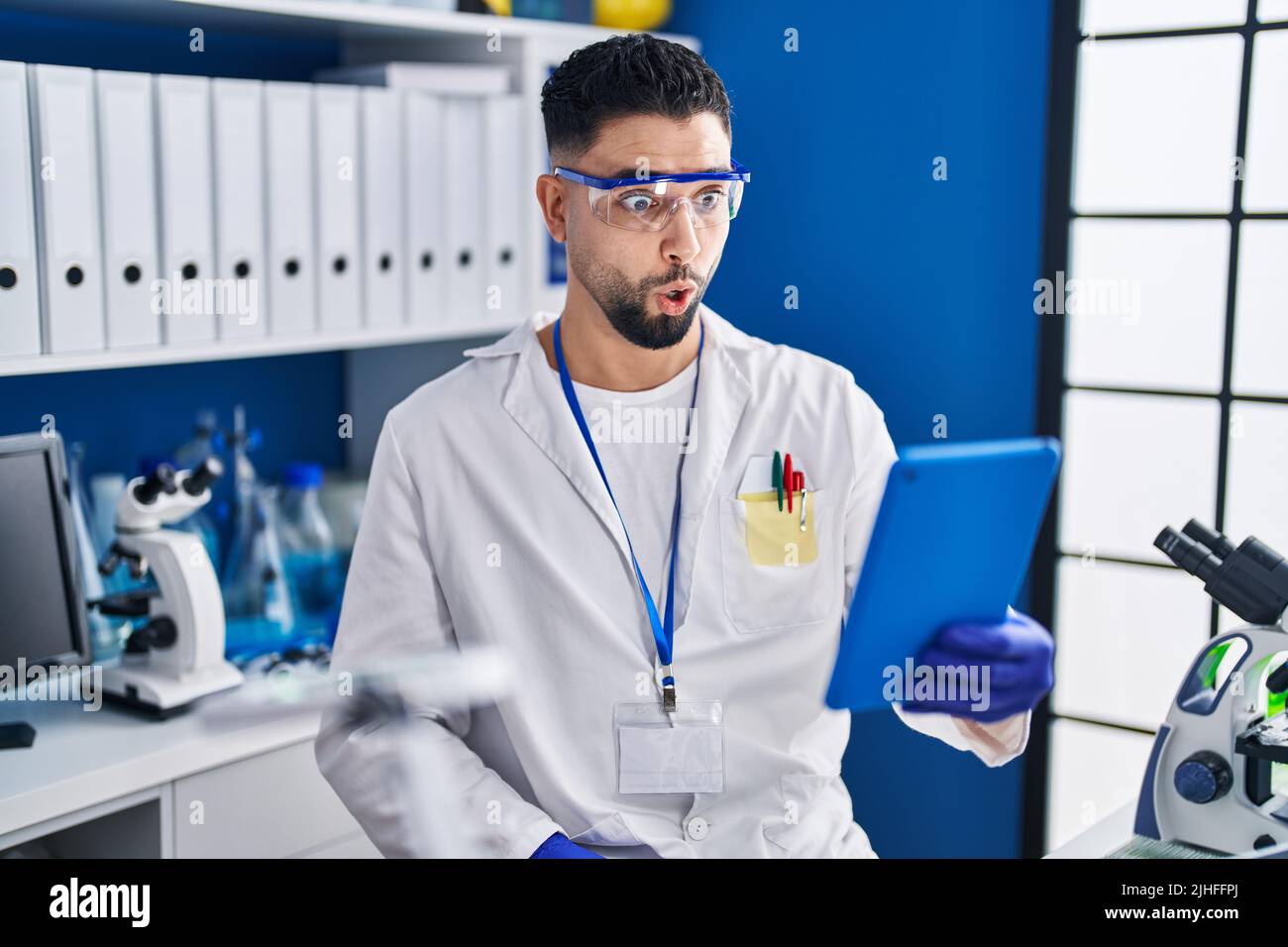 Young handsome man working at scientist laboratory doing online call ...