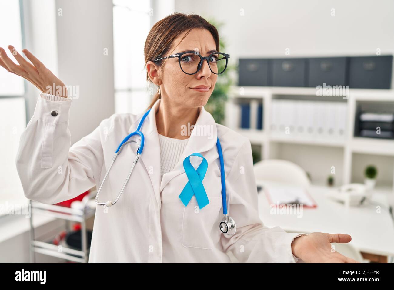 Young brunette doctor woman wearing stethoscope at the clinic clueless ...