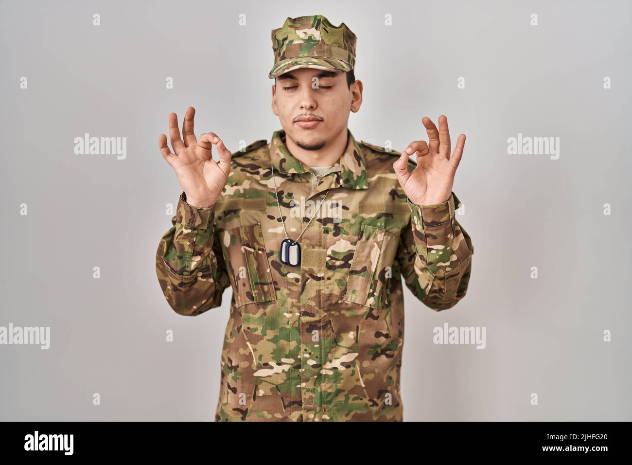 Young arab man wearing camouflage army uniform relaxed and smiling with ...