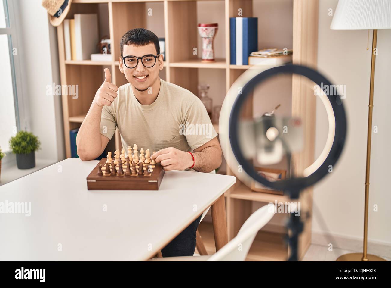 Young arab man doing chess tutorial smiling happy and positive, thumb ...