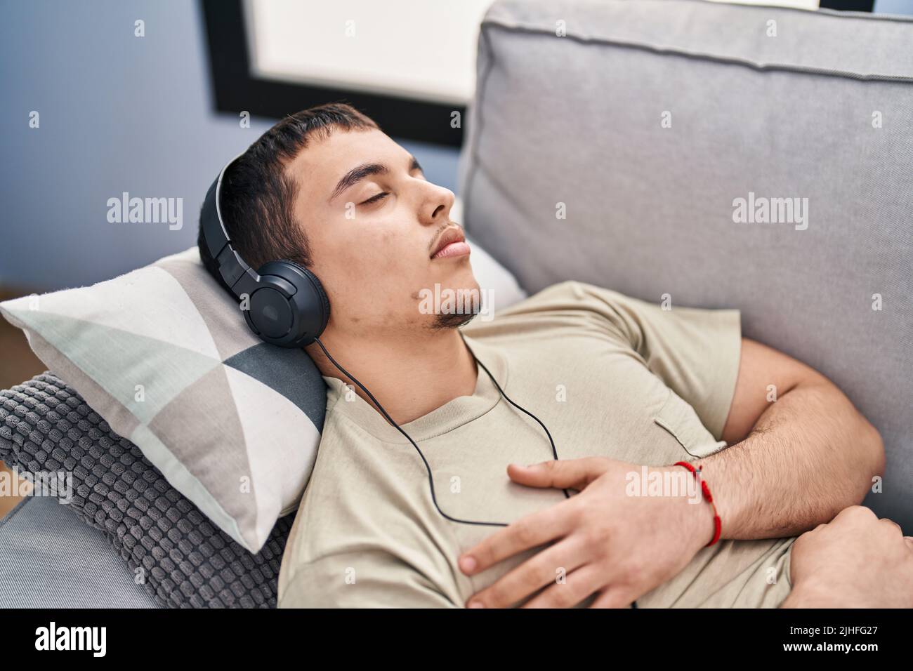 Young man listening to music sleeping on sofa at home Stock Photo - Alamy