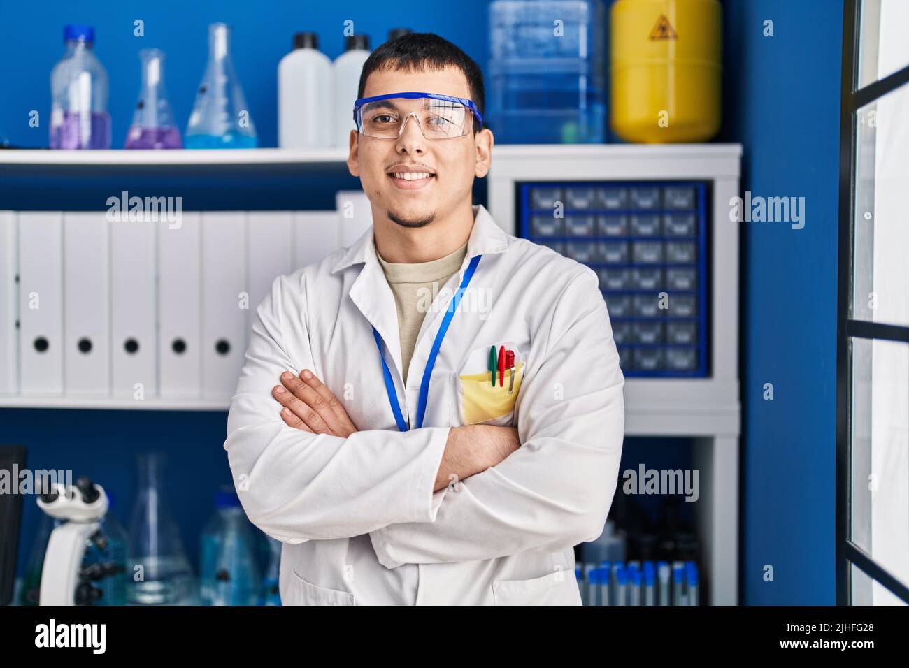 Young man scientist smiling confident standing with arms crossed gesture at laboratory Stock ...