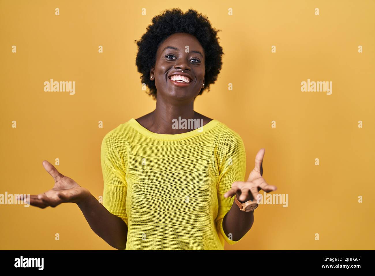 African young woman standing over yellow studio celebrating crazy and ...