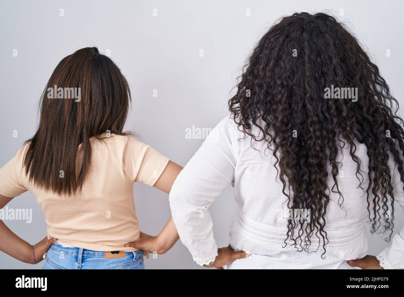 Mother and young daughter standing over white background standing ...