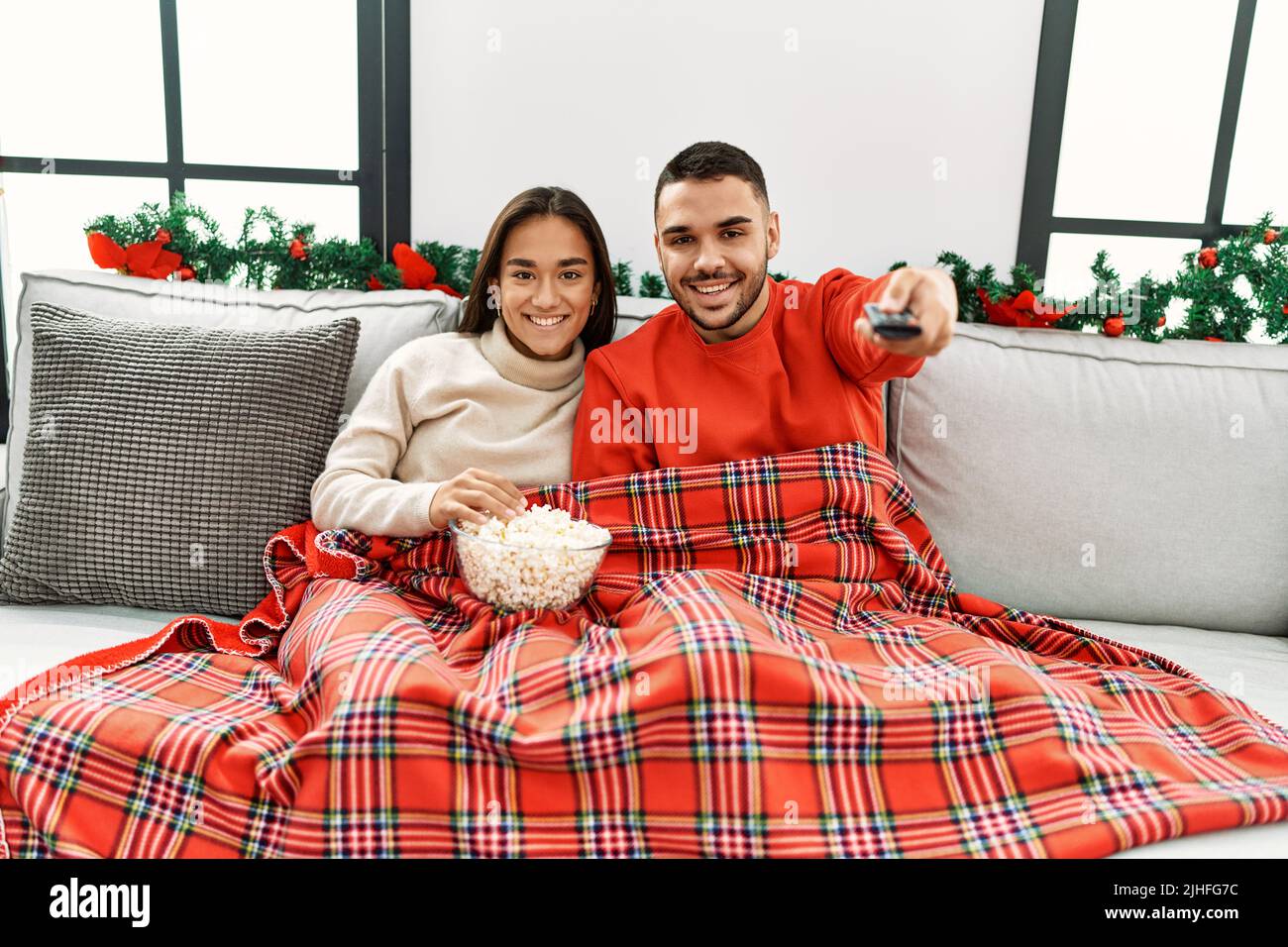 Young hispanic couple watching movie sitting on the sofa at home Stock ...