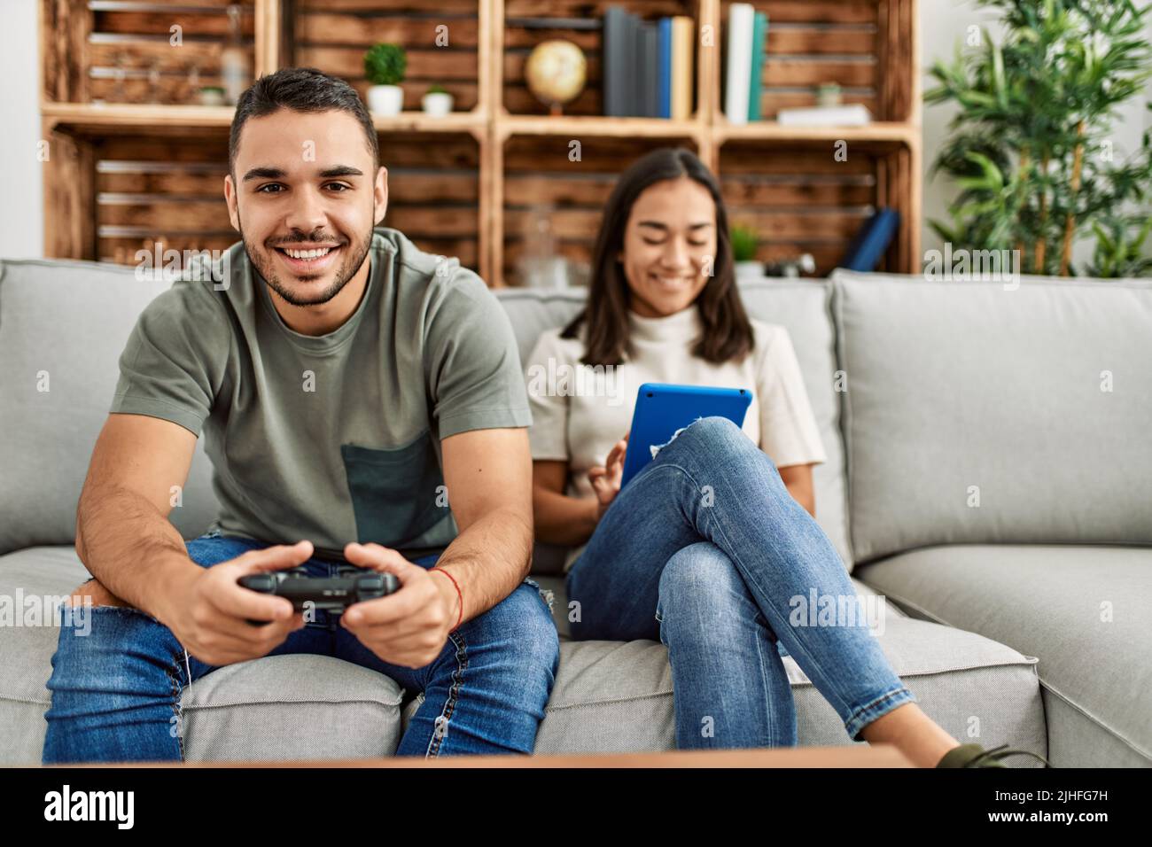 Young latin couple playing video game and using touchpad at home Stock ...