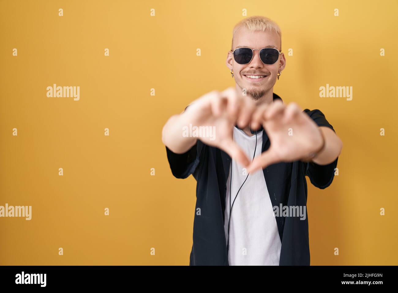 Young caucasian man wearing sunglasses standing over yellow background ...