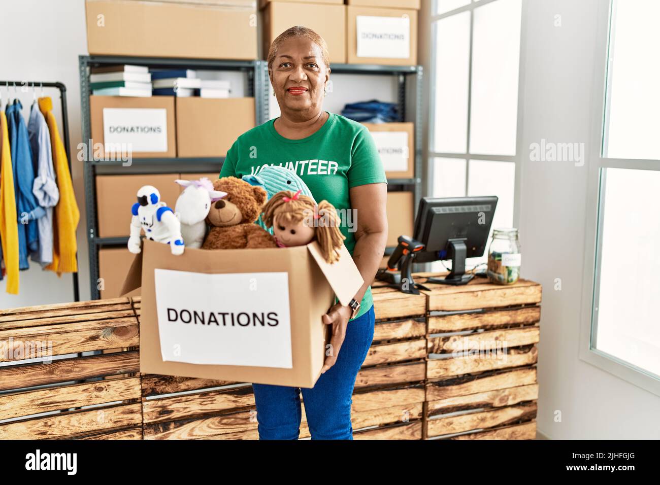 Senior african american woman wearing volunteer uniform holding toys ...