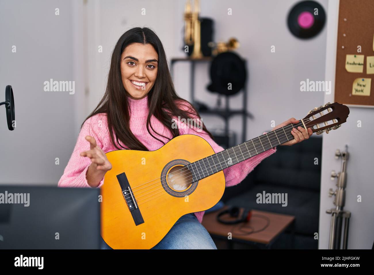 Young brunette woman playing classic guitar at music studio celebrating ...